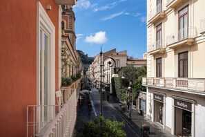 Vista da rua com edifícios, céu claro e uma loja MaxMara.