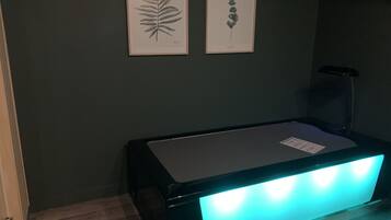 Quarto com uma cama, luminária fixada na parede e duas impressões botânicas emolduradas.