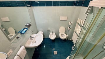 Casa de banho com lavatório, duas sanitas, bidé e cabine de duche em vidro.