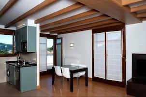 Uma cozinha moderna com fogão embutido, uma área de jantar com mesa e cadeiras, e uma grande porta de vidro deslizante que dá para uma varanda.