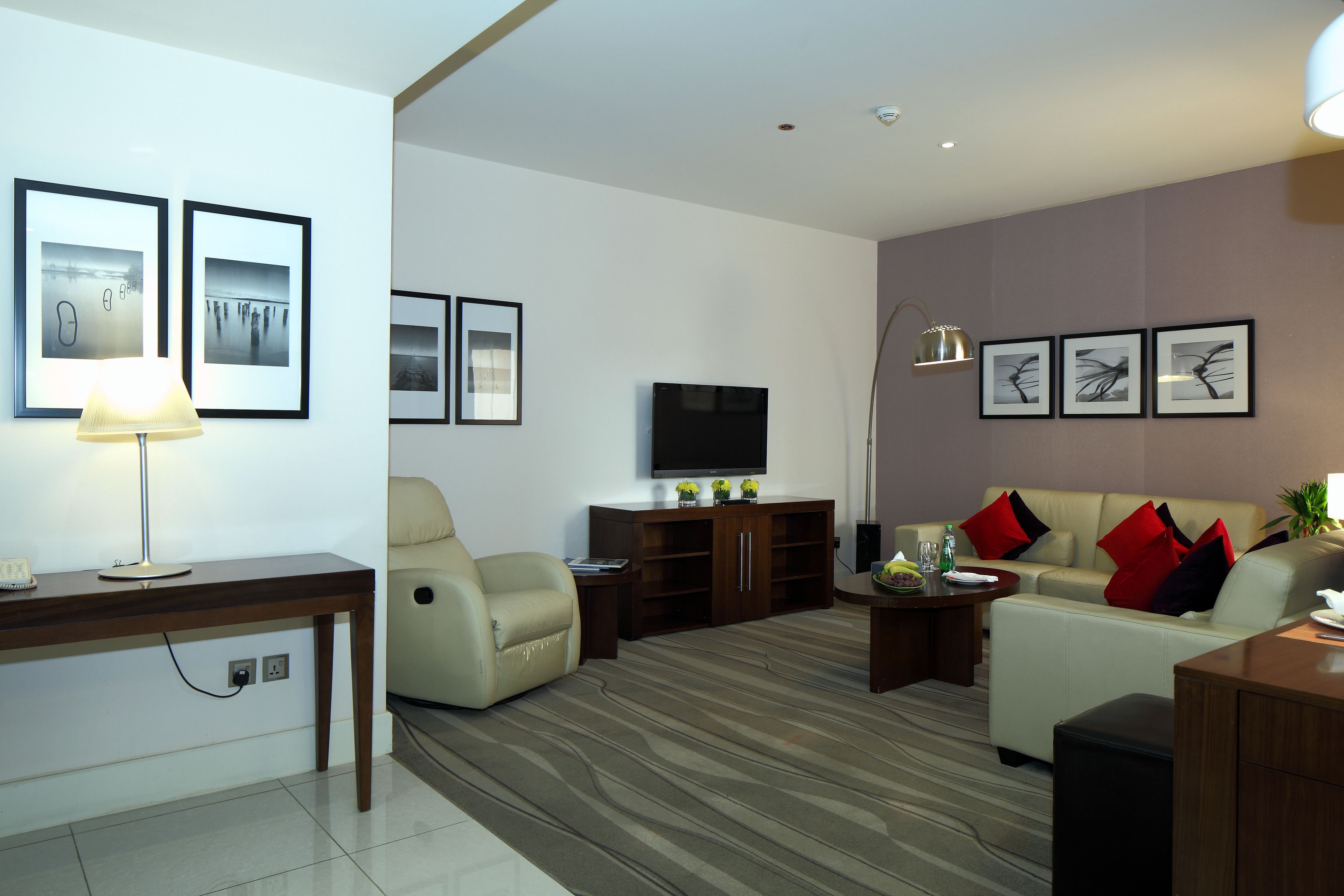 Uma sala de estar moderna com sofá, poltrona, televisão e quadros na parede.