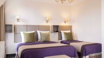 Quarto de hotel com duas camas, cada uma com cabeceira, mesa de cabeceira e abajur.