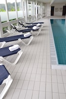 Uma área ao lado da piscina com espreguiçadeiras e piscina.