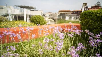 Um jardim no terraço com flores roxas e grama verde.