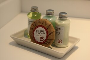 Uma bandeja com três frascos de sabonete líquido e um saco de papel marrom com etiqueta.