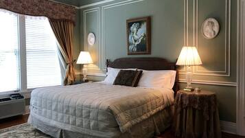 Um quarto bem arrumado com uma cama grande, duas luminárias de cabeceira, um relógio de parede decorativo e uma janela com cortinas.