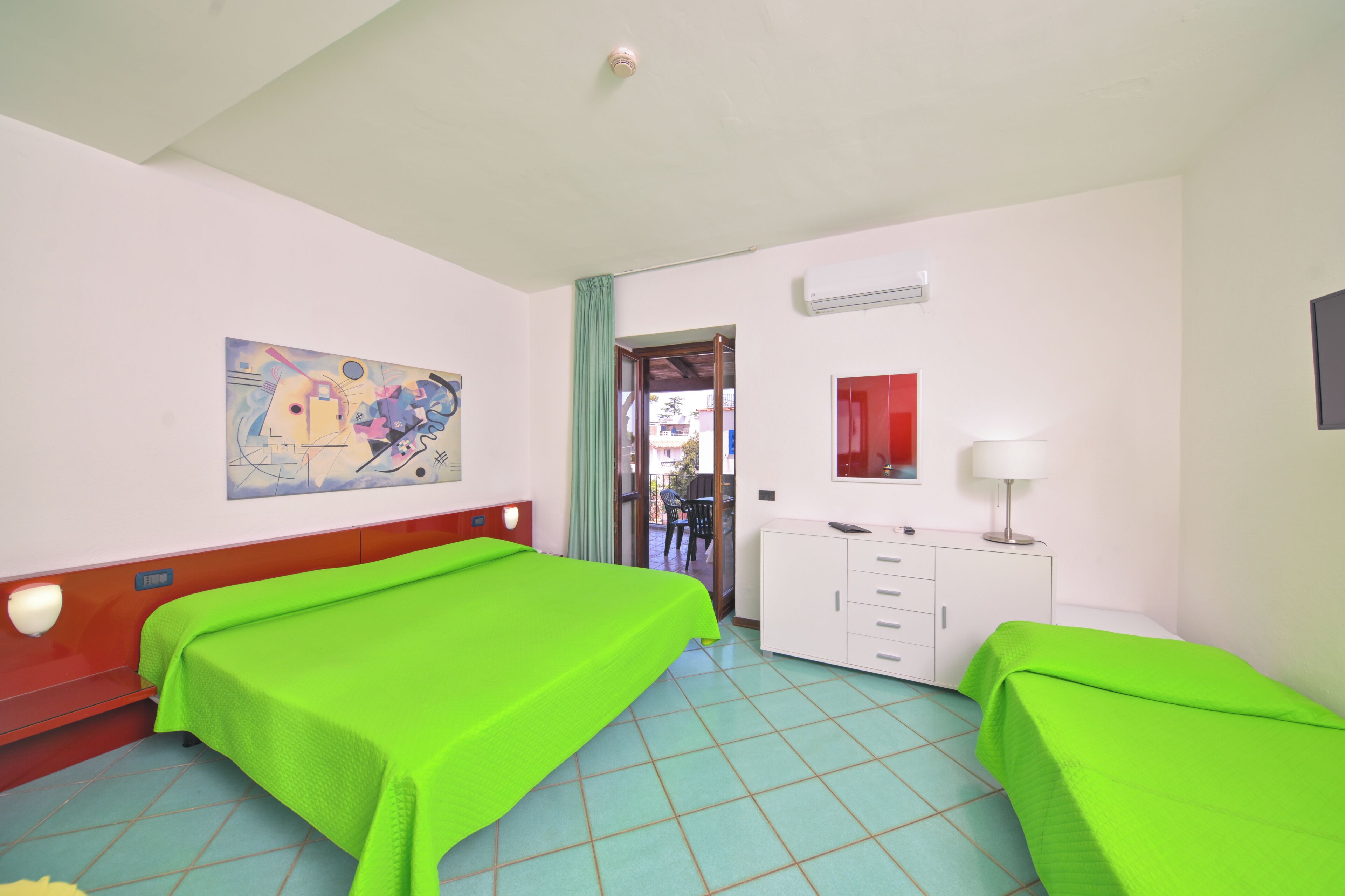 Quarto com duas camas, uma escrivaninha, uma cadeira, um quadro e uma janela.
