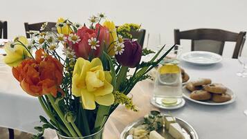 Uma mesa posta com um vaso de vidro com flores, pratos de comida e um copo de água.