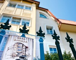 Um edifício com uma placa visível que diz "MAIA ANGLIA" e uma cerca de metal decorativa na frente.