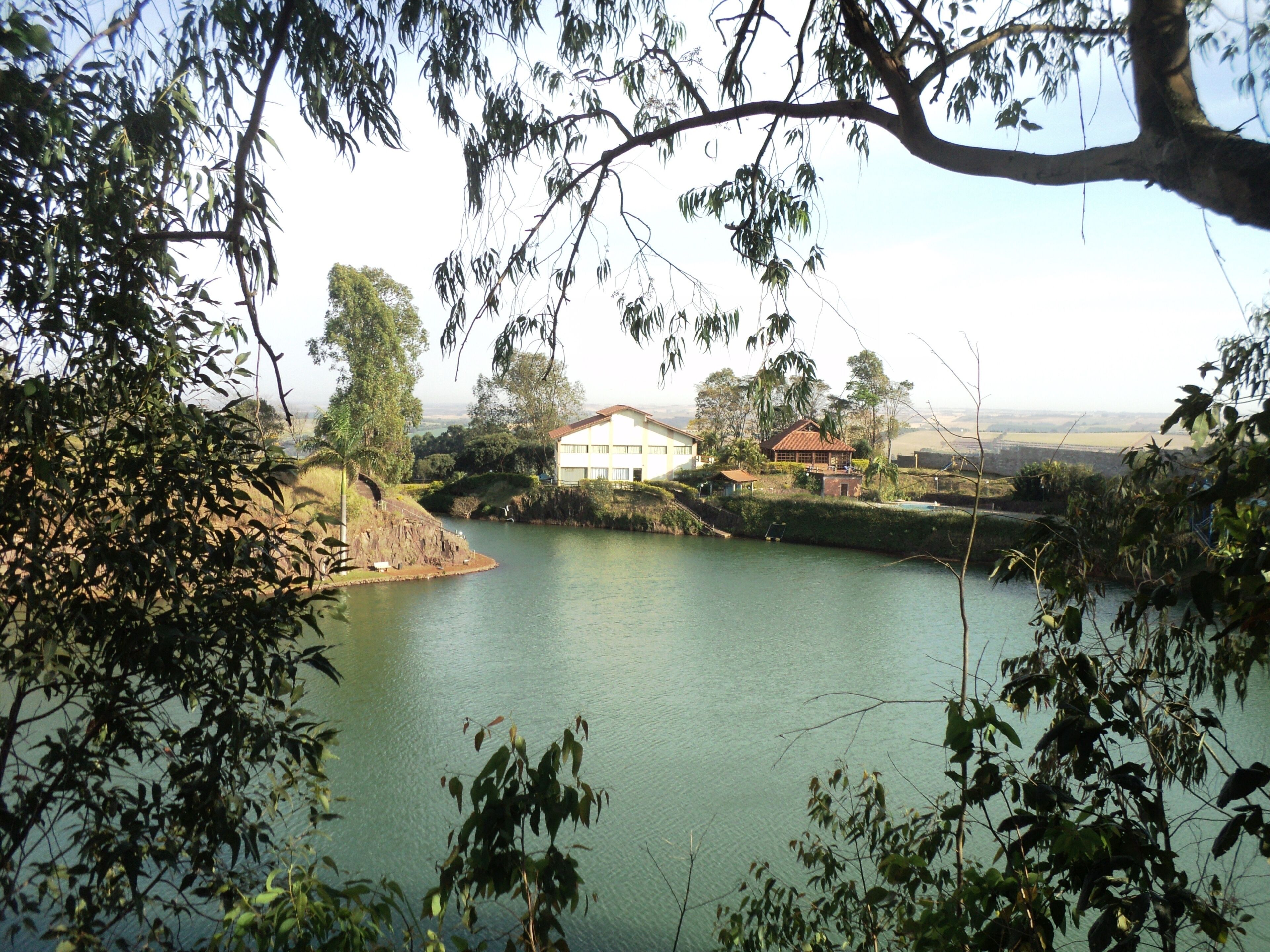 Um lago com uma casa e um edifício ao fundo.