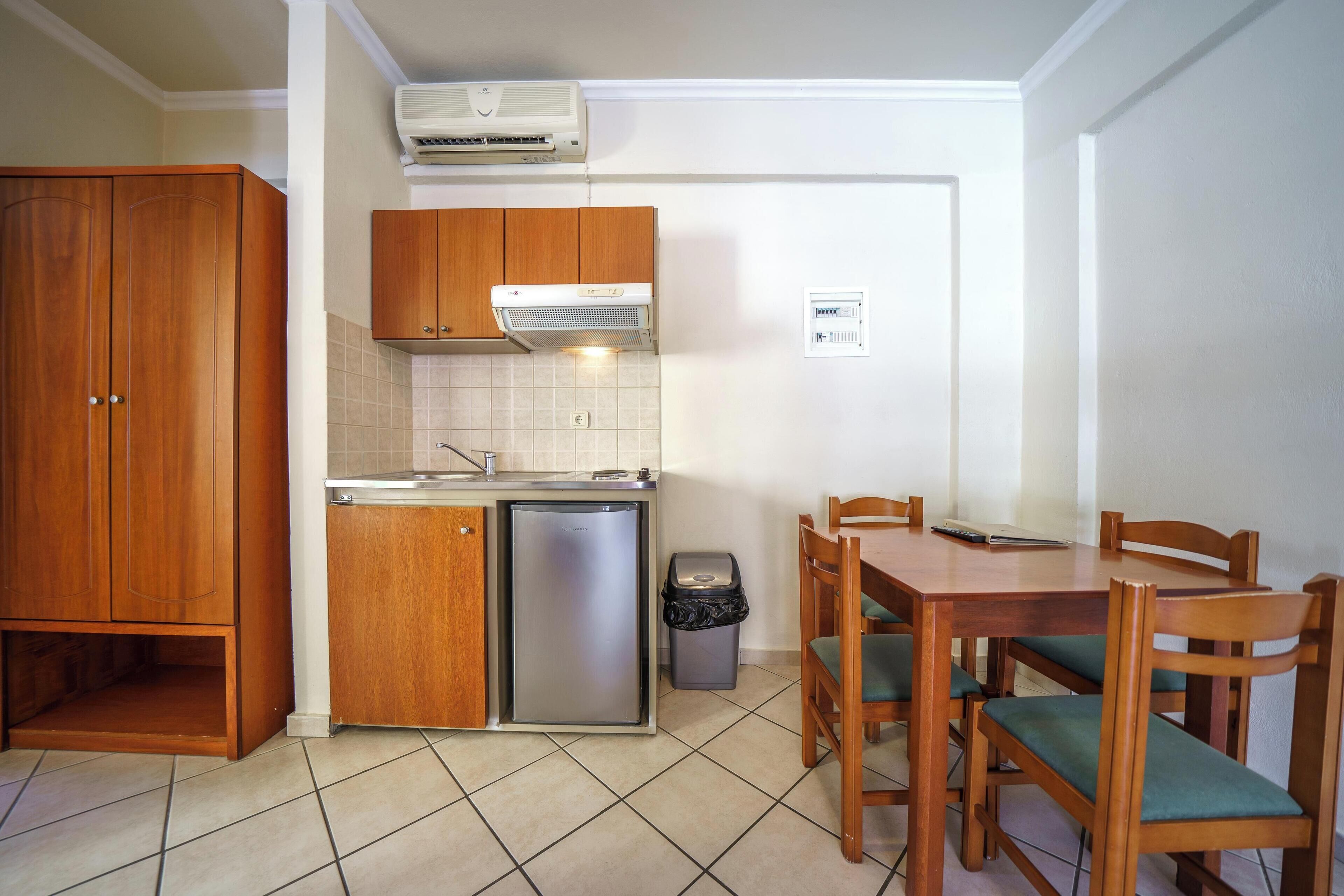 Cozinha compacta com armários de madeira, máquina de lavar louça embutida e área de refeições com mesa e cadeiras.