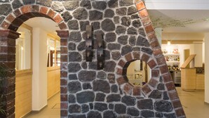 Pareda de pedra com um espelho circular e um arco de madeira em um espaço interior moderno.