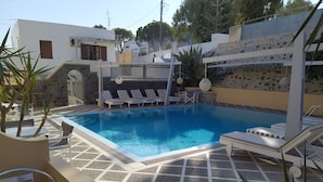Piscina com espreguiçadeiras e um pérgola.