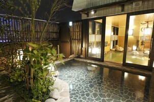 Uma área moderna de piscina ao ar livre com piso de mosaico, cercada por um gramado e vegetação exuberante.