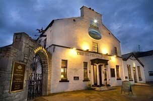Hotel Silverdale com entrada em arco de pedra, uma placa acima da porta e fachada bem iluminada.