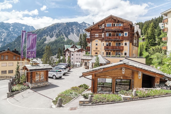 Um resort na montanha com construções de madeira, área de estacionamento e vista para montanhas cobertas de neve.