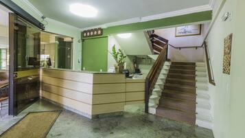 Uma área de recepção com balcão, escada e parede verde.