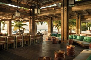 Um bar à beira-mar com móveis de madeira e vista para o oceano.