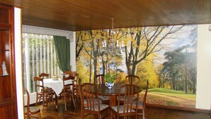 Uma área de refeições com uma janela grande, mesa de madeira e cadeiras.