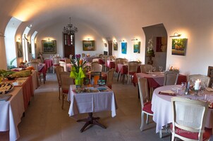 Restaurante com várias mesas e cadeiras, cada conjunto com copos de vinho e pratos.