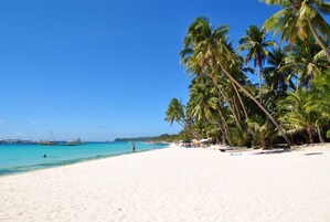 Na praia, praia de areia branca, espreguiçadeiras, guarda-sóis de praia 