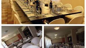Uma sala de jantar com mesas longas preparadas para um evento formal, com cadeiras brancas e design de interiores clássico.
