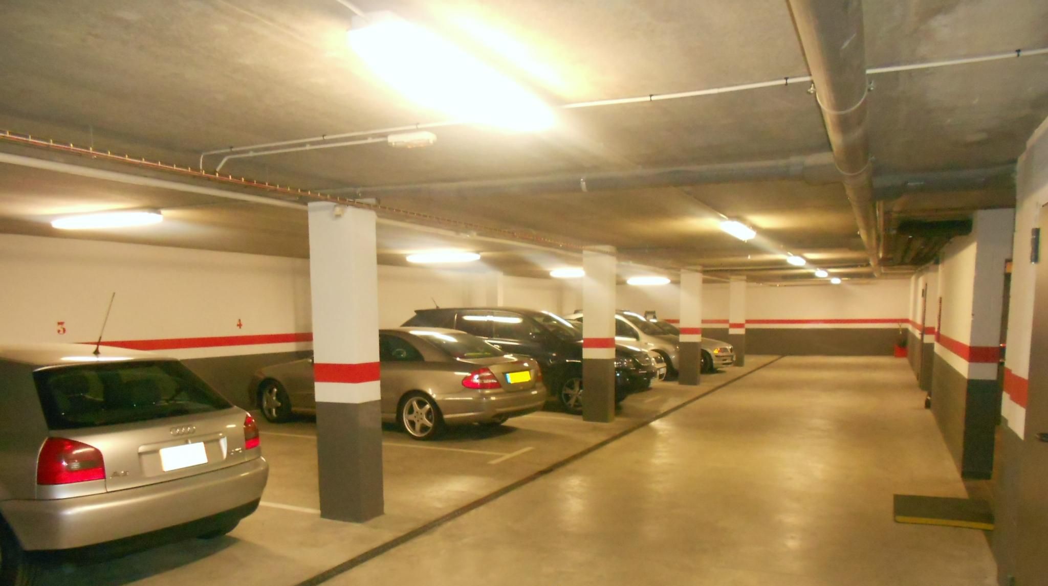 Um estacionamento interno com vários carros estacionados e pilares.