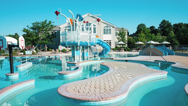 Piscina com escorregador, espreguiçadeiras e basquete.