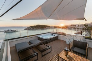 Um terraço com hidromassagem, espreguiçadeiras e uma mesa com garrafa e copo.