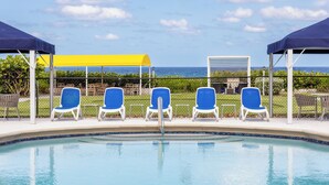 Uma área de piscina com cadeiras azuis e um toldo amarelo.