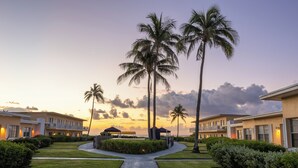 Um resort com uma passagem central, palmeiras e edifícios com varandas.