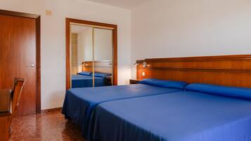 Quarto de hotel com duas camas, cabeceira de madeira, espelho e uma porta.