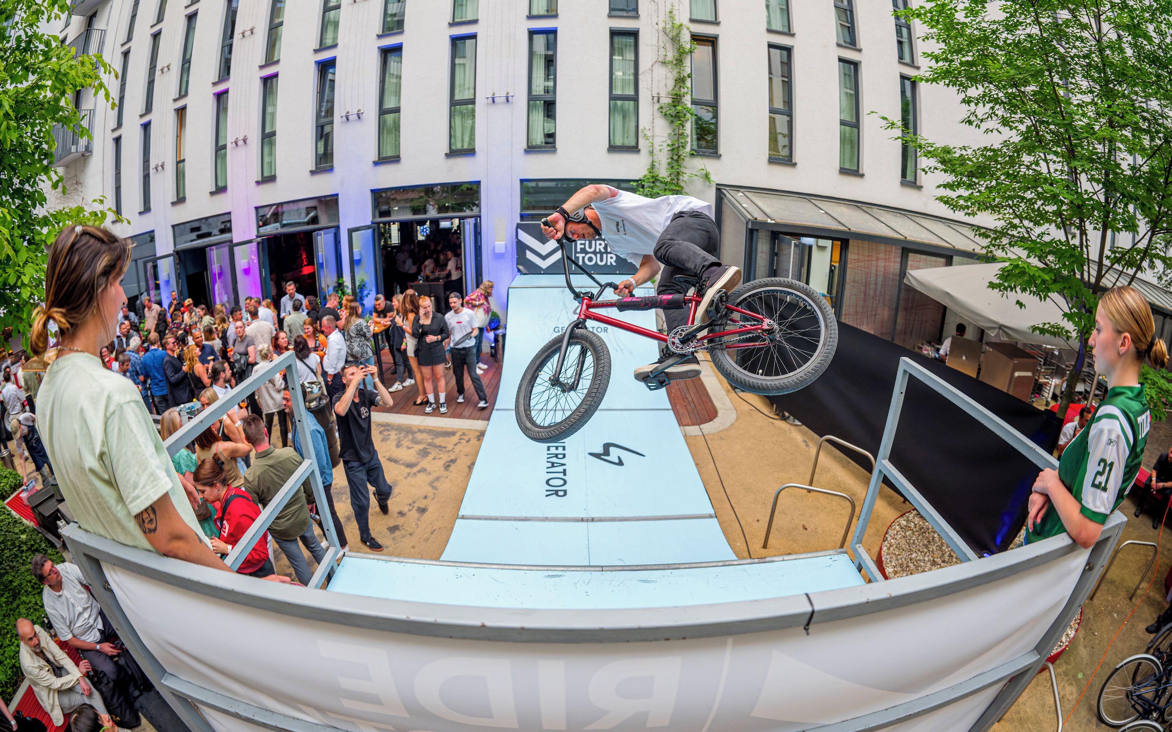 Um ciclista de BMX executando uma manobra numa rampa, com uma plateia a assistir.