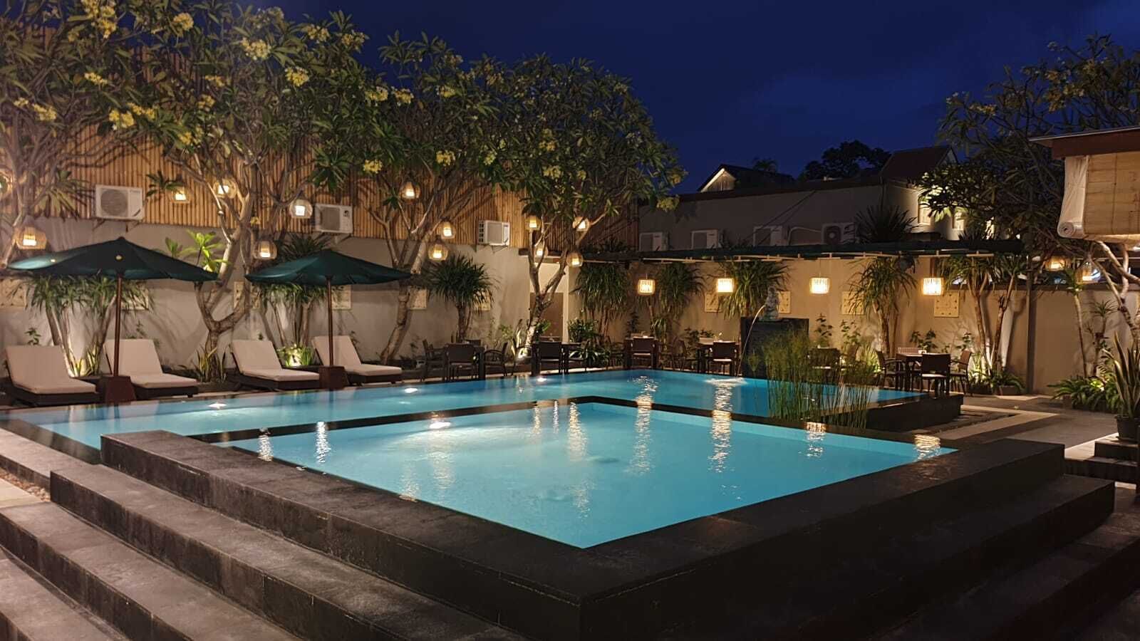 Piscina retangular com degraus de acesso, rodeada por espreguiçadeiras e guarda-sóis.