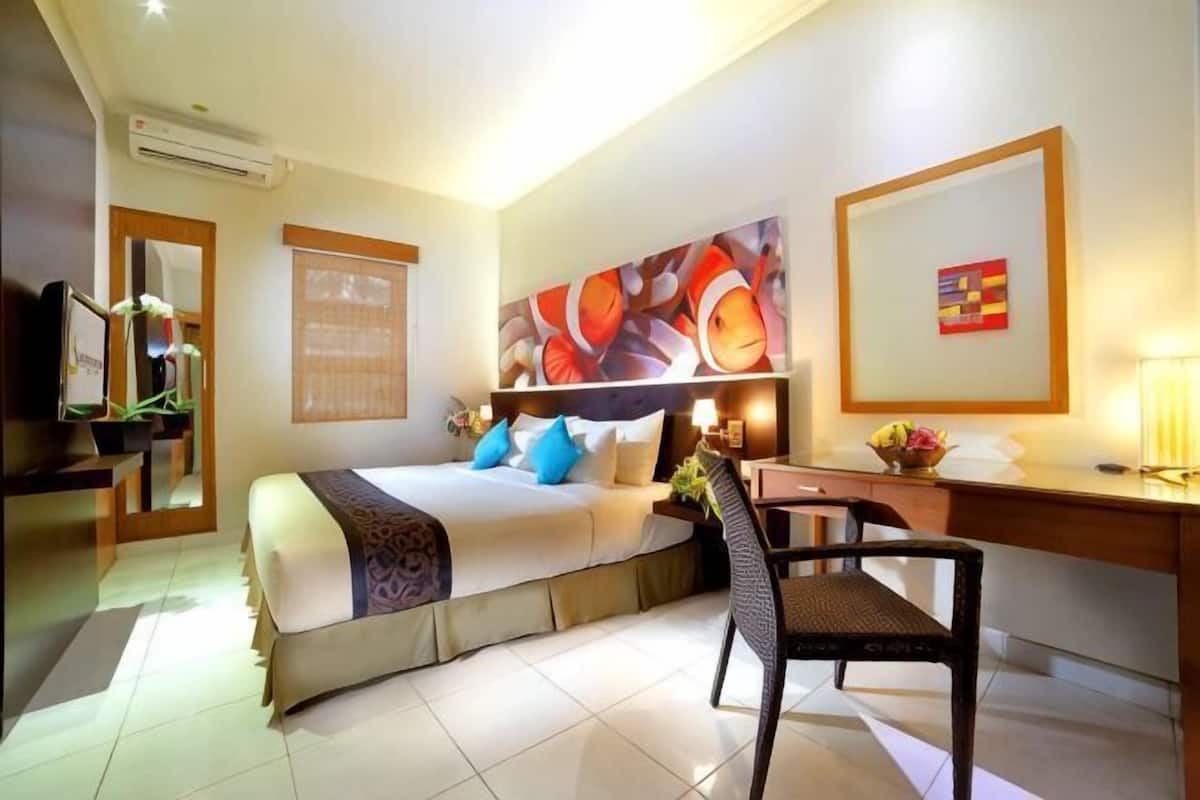 Quarto de hotel com cama, escrivaninha, cadeira e obras de arte nas paredes.