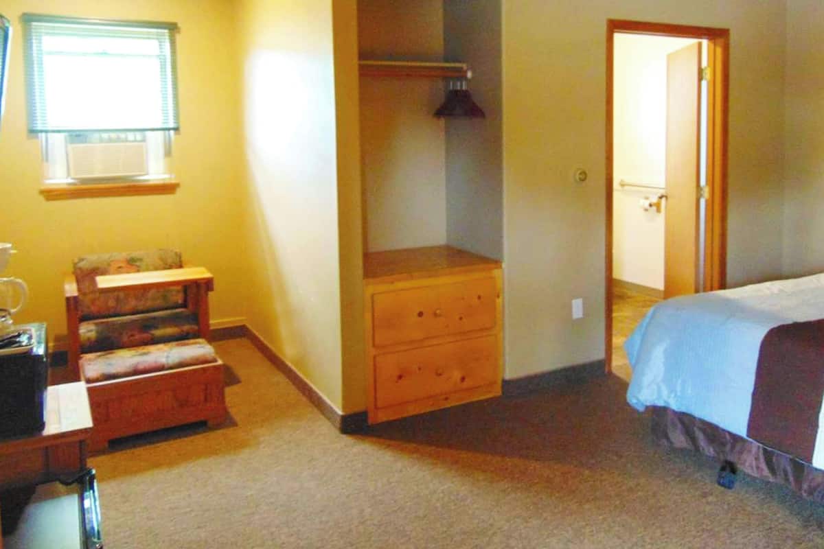 Quarto com cama, penteadeira, cadeira e armário.