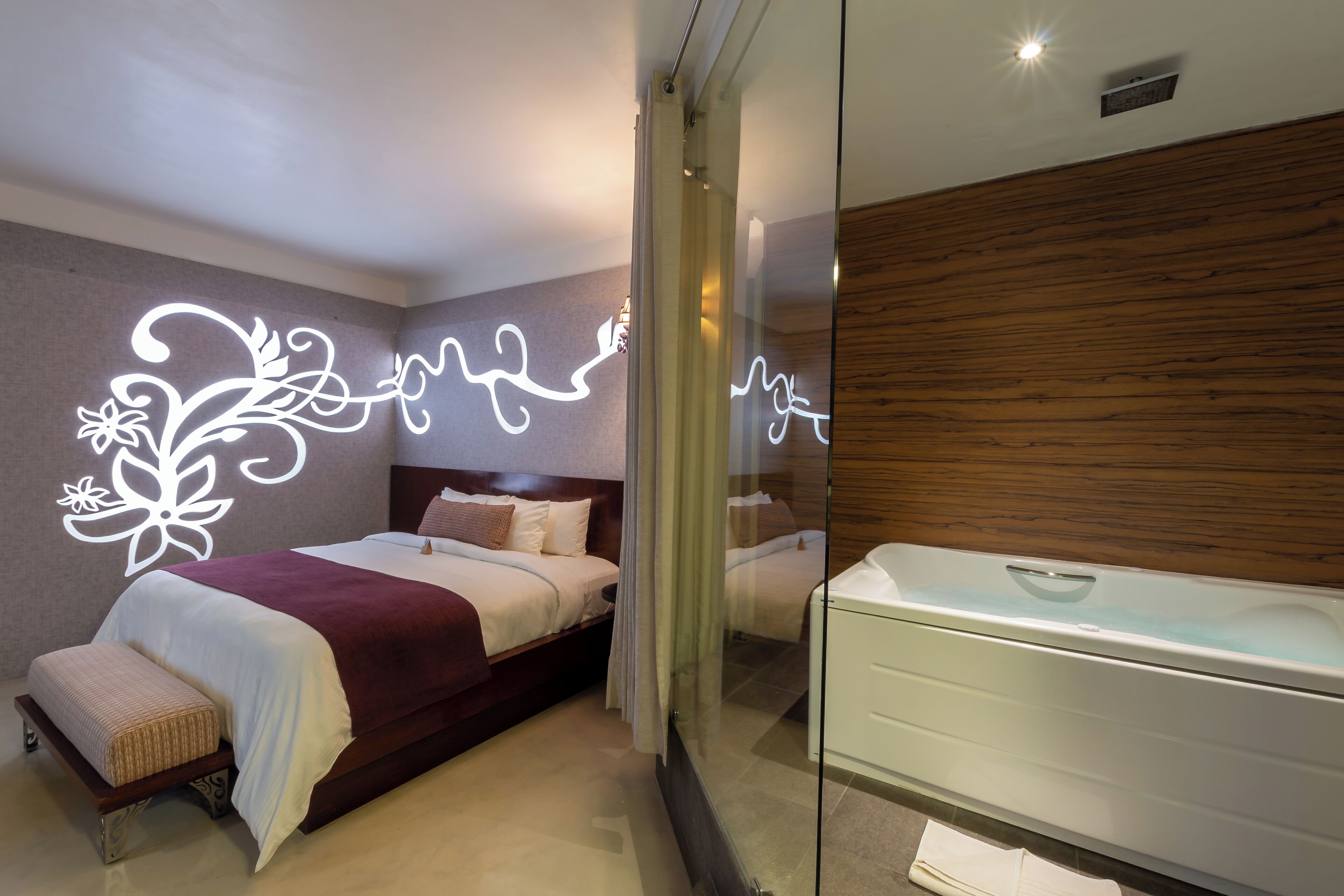 Quarto moderno com uma cama grande, box de vidro e design decorativo na parede.