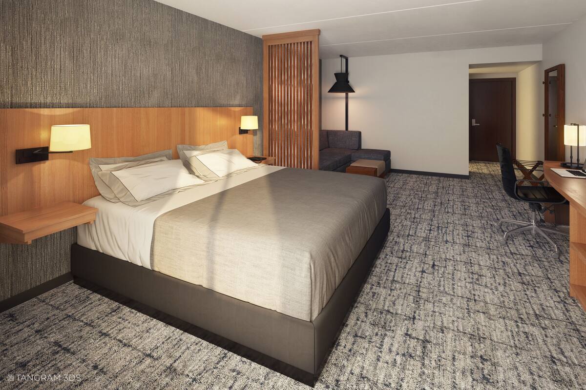 Quarto de hotel moderno com uma cama grande, uma escrivaninha, uma cadeira e uma pequena área de estar.