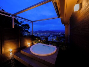 Um banheiro moderno com uma banheira separada, vista para a cidade e decoração em madeira.