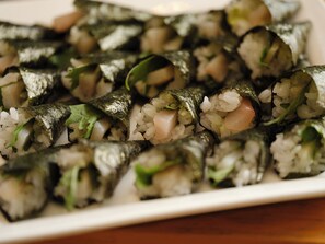 Uma travessa de sushi com arroz e peixe, decorada com folhas verdes.