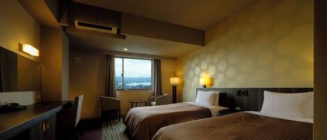 Quarto de hotel com duas camas, uma escrivaninha, uma cadeira e janela com vista.