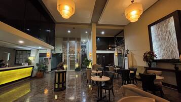 Um saguão de hotel com balcão de recepção, área de estar e escadas para um andar superior.