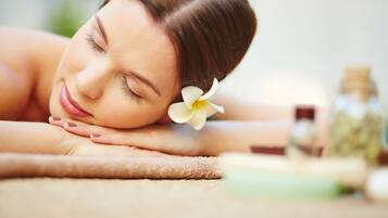 Uma pessoa deitada em uma mesa de massagem com uma flor ao lado.