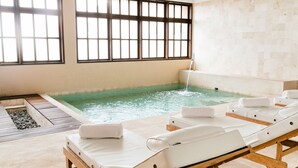 Área de spa com hidromassagem, espreguiçadeiras e vista através de amplas janelas.