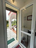 Entrada de um quarto de hotel com uma porta de vidro deslizante que dá para um pátio.