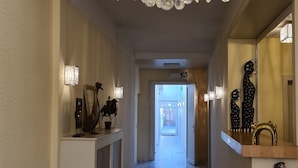 Corredor com lustre, área de estar e espelho.