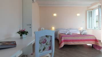 Um quarto com cama, mesas de cabeceira, uma cadeira, escrivaninha e janela.