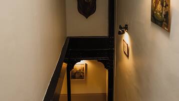 Uma escadaria com um chifre de veado montado na parede, um quadro emoldurado e iluminação na parede.
