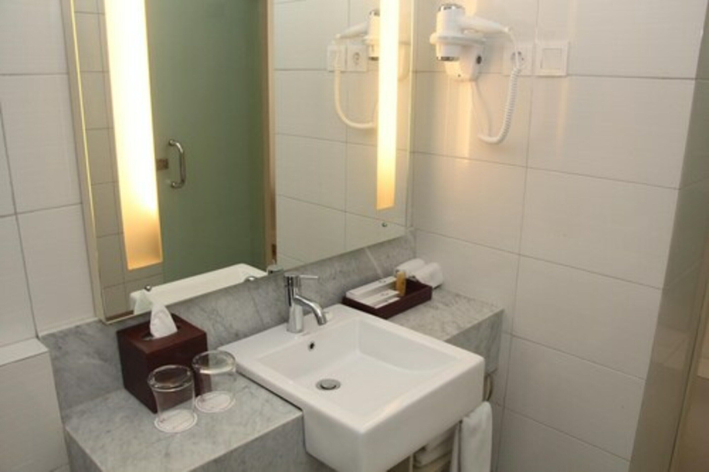 Uma casa de banho moderna com uma pia branca, um espelho e um porta-toalhas.