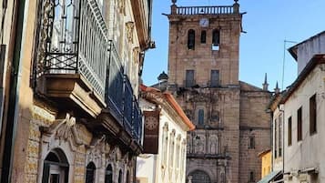 Uma rua de pedras que leva a um edifício histórico com uma torre do relógio.